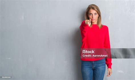 아름 다운 젊은 여 서 그런 지 회색 벽 카메라 하 고 당신에 게 손가락으로 가리키는 입고 겨울 스웨터 손 기호 정면에서 긍정적이 고 자신감 제스처 가리키기에 대한 스톡