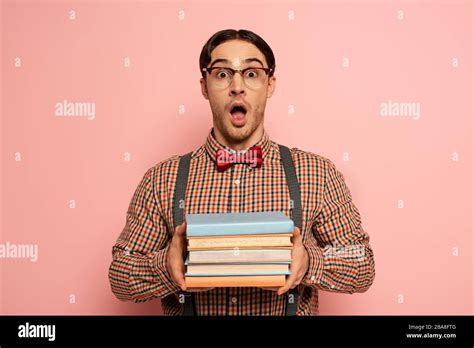Shocked Male Nerd With Open Mouth In Eyeglasses Holding Books On Pink Stock Photo Alamy
