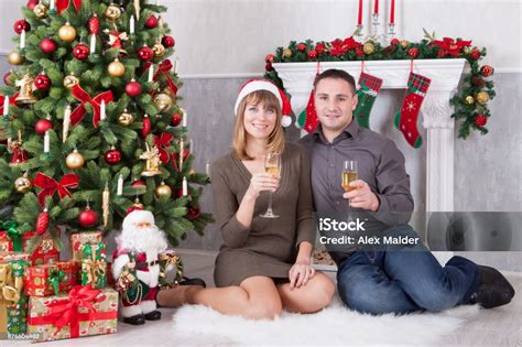 크리스마스 또는 새 해 축 하 아름 다운 영 커플 크리스마스 선물 크리스마스 트리 근처에 앉아 샴페인 잔 배경에 스타킹 크리스마스와 벽난로 2명에 대한 스톡 사진 및 기타