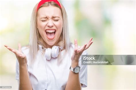 젊은 금발의 여 자가 착용 하는 헤드폰을 통해 음악을 듣고 절연 배경 화 축 하 하 고 무기와 성공을 위해 미친 제기 흥분 비명 눈을 폐쇄 우승자 개념 금발 머리에 대한