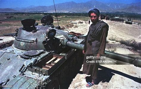 A Turbaned Taliban Fighter Stands By An Aged Soviet Made Tank At A