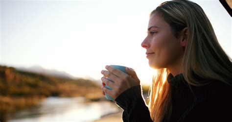 여자는 여름에 강가에서 커피를 마시며 생각에 잠긴다 휴일에 일출에 모형 젊은 여성과 차 뜨거운 음료와 야외 캠핑에서 자유와 함께 여행과 휴가 25 29세에 대한 스톡 사진