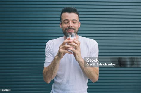 행복 한 사람은 서 있고 밀의 유리를 들고 있다 그는 눈을 감고 순간을 즐기는 것을 유지 하 고 있습니다 줄무늬와 파란색 배경에 고립입니다 가능성에 대한 스톡 사진 및 기타