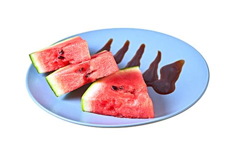 붉은 잘 익은 육즙 펄프 삼각형의 형태로 신선한 수박의 세 조각은 그림자없이 흰색 배경에 고립 녹은 초콜릿이나 크림으로 장식 된 둥근 세라믹 접시에 놓여 있습니다 0명에