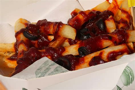 바베큐 소스와 블랙 올리브 슬라이스를 얹은 신선한 바삭바삭한 감자 튀김 칩 건강에 해로운 스낵 음식 높은 전망의 골판지 콘