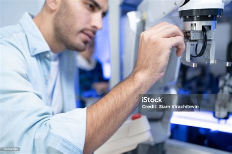 자동화 로봇 팔 기계를 제어하는 파란색 셔츠를 입은 젊은 백인 남성 산업 엔지니어의 전면 보기 25 29세에 대한 스톡 사진 및 기타 이미지 Istock