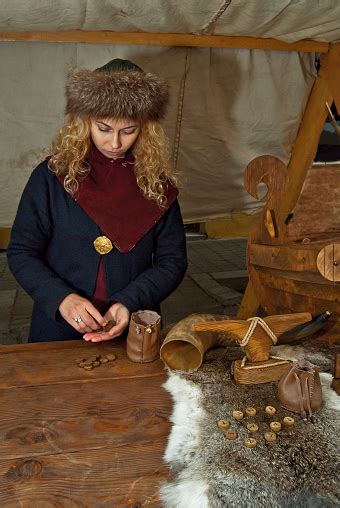 푸른 눈을 가진 소녀는 룬에 경이로움 중세 축제에서 바이킹 의상을 입은 금발 북부 민족의 정통 의류와 라이프 스타일 나무 테이블에 모피 고대의에 대한 스톡 사진 및 기타