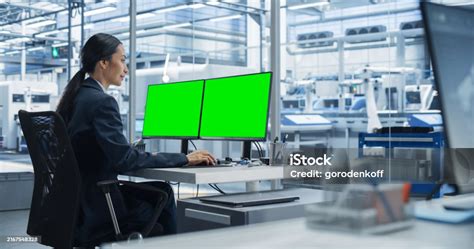 공장 사무실에서 그린 스크린 크로마키 모형 디스플레이가 있는 데스크톱 컴퓨터에서 작업하는 여성 로봇 기술자 기술 연구 자율 조립 라인을 갖춘 개발 시설 개발에 대한 스톡