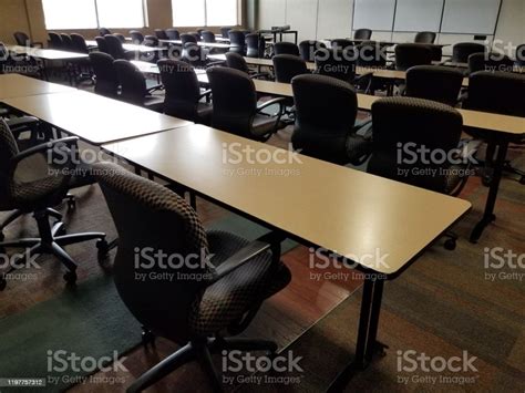 Classroom With Long Tables And Chairs Lined Up View From Back Stock
