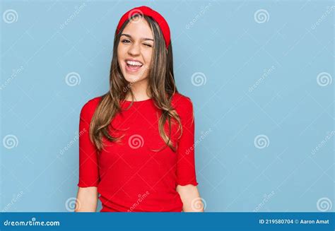 Young Brunette Woman Wearing Casual Clothes Winking Looking At The Camera With Expression