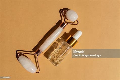 베이지 색 배경에 24k 골드 세럼 병으로 장미 석영으로 만든 얼굴을위한 마사지 롤러 가정에서 스킨 케어의 개념 금색에 대한 스톡 사진 및 기타 이미지 Istock