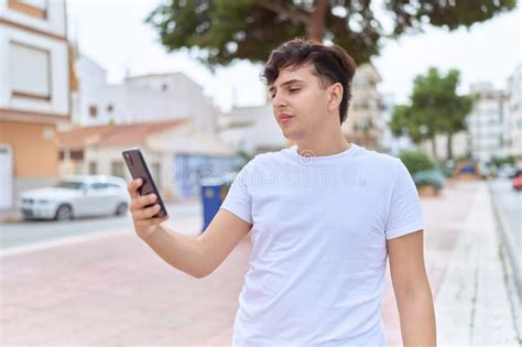 Non Binary Man Using Smartphone With Relaxed Expression At Park Stock