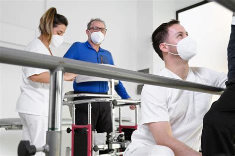 장애인 백인 노인이 재활 센터에서 평행 막대기로 걸을 수 있도록 돕는 물리 치료사 고품질 사진 30 34세에 대한 스톡 사진 및 기타 이미지 Istock