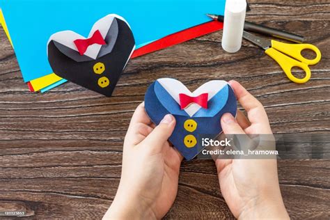 아이는 나무 테이블에 턱시도와 아버지의 날에 대한 인사말 카드를 손에 들고있다 손으로 만든 어린이 창의력 프로젝트 공예 아이들을위한 공예 개념에 대한 스톡 사진 및 기타