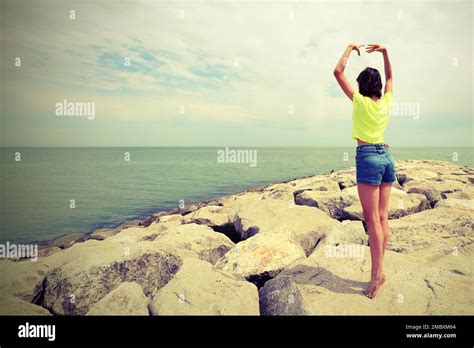 Young Girl Performs Gymnastic Exercises On The Rocks By The Sea With