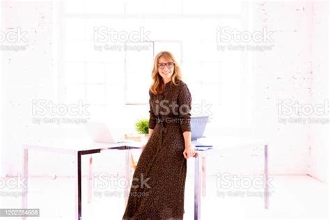 카메라를 보고 미소를 지으며 사무실 책상에 서있는 매력적인 미소 사업가의 샷 40 49세에 대한 스톡 사진 및 기타 이미지 40 49세 50 59세 갈색 머리