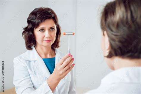 Neurological Examination The Neurologist Testing Reflexes On A Female Patient Using A Hammer
