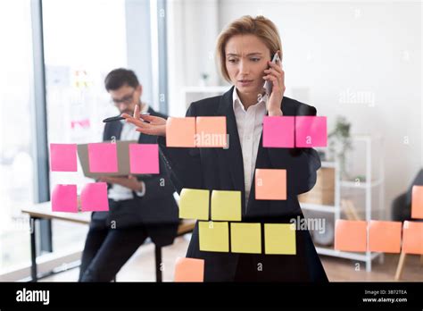 Business Professionals Collaborating With Sticky Notes On Glass Board