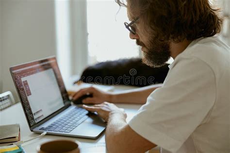 Close Up Of Focused Male Programmer Sitting At Desk And Working Laptop