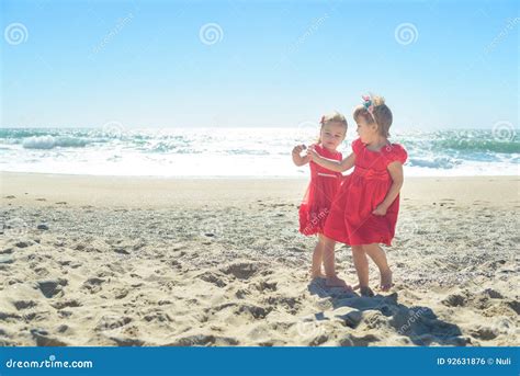 Twee Meisjes In Rode Kleding Op Het Strand Stock Foto Image Of Strand