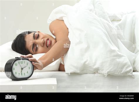 Woman Turning Off Alarm Clock Stock Photo Alamy