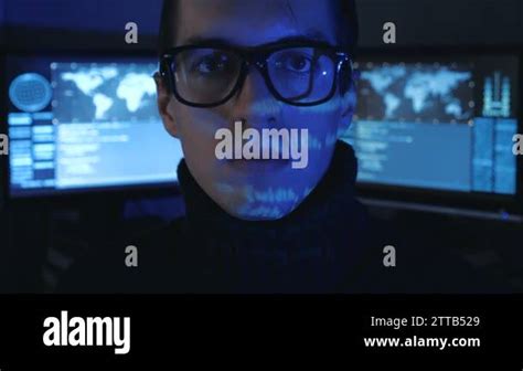Portrait Of Hacker Programmer In Glasses Looks At Camera While Blue Code Characters Reflect On