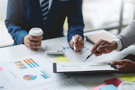 회의에서 계획 분석 보고서와 함께 새로운 프로젝트에 함께 일하는 비즈니스 사람들 그룹 그래프를 가리키며 함께 모인 사업가들은 사업 이익을 평가합니다 2명에 대한 스톡 사진