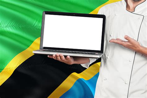 탄자니아 국기 배경에 빈 화면으로 노트북을 들고 탄자니아 요리사 복사 공간에 대 한 유니폼과 포인팅 노트북을 입고 요리 고급 요리에 대한 스톡 사진 및 기타 이미지 Istock