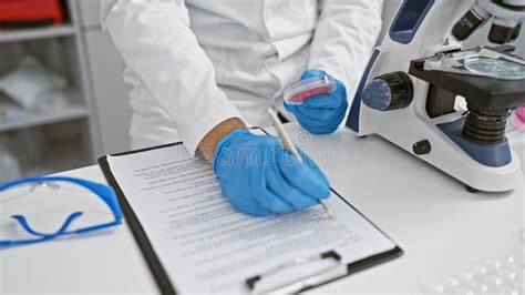 Cropped View Of A Scientist In A Laboratory Analyzing Specimens With A Microscope And Taking