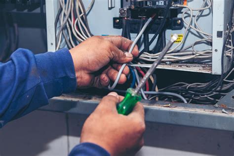 검사관은 배전반 기계 유지 보수 서비스를 제공합니다 전기 기계 기술자는 와이어 전기 캐비닛을 확인합니다 전기 회로 수리 전압 작동 남자 손 고정 차단기 일함에 대한 스톡