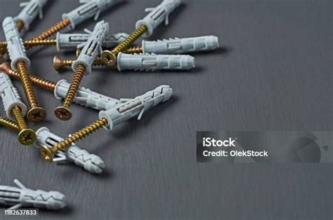 벽에 다른 Predmet을 고정하기위한 광택 나사 황금 색과 새로운 플라스틱 회색 다웰의 흩어져 많은 작업장에서 스크래치 어두운 콘크리트 테이블에 놓여있다 텍스트를 위한