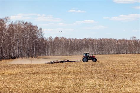 푸른 하늘 맑은 봄 날 아래 노란 색의 농업 산업에 대 한 깎고 및 잡 초 필드에 대 한 개척 쟁기와 빨간 트랙터 작물 농촌 기술을 심기 위한 준비 농업 각도에 대한 스톡