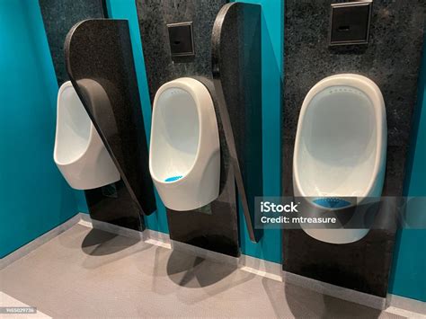 공중 화장실 화장실의 줄 소변기 파란색 Pvc가 있는 흰색 세라믹 소변기 그릇에 담긴 향기로운 소변기 스크린 배경 스플래시 백 벽 내부에 배수구와 배수구가 있는 깨끗한 위생