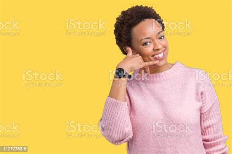 격리 된 배경 위에 아름 다운 젊은 아프리카계 미국인 여자는 전화와 얘기 같은 손과 손가락으로 전화 제스처를 하 고 웃 고