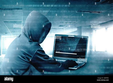 Hacker In Black Hoodie Using Laptop On The Desk To Hacking System With