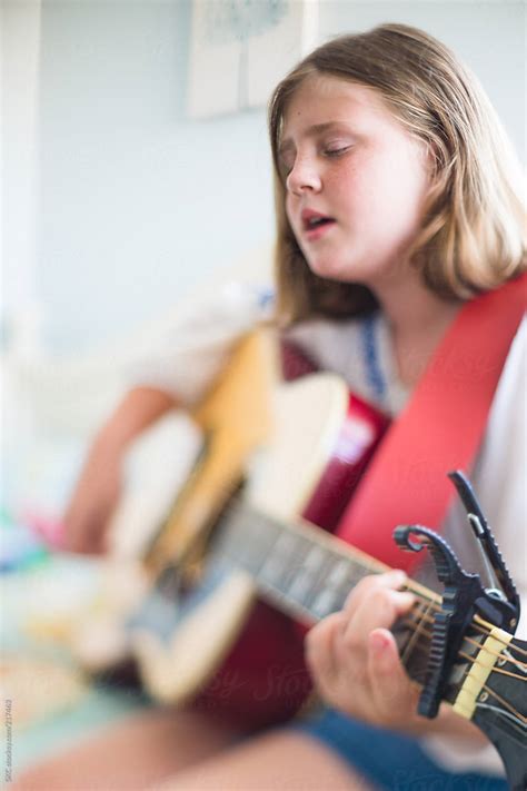 Girl Practicing Her Guitar And Singing In Her Bedroom By Stocksy