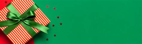 녹색 리본과 홀로그램 반짝이 색종이 붉은 녹색 배경 상단보기에있는 별의 색종이 모양의 선물 상자는 텍스트를위한 공간을 평평하게