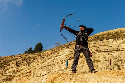 Premium Photo Man With Bow And Arrow Practicing Archery In Park