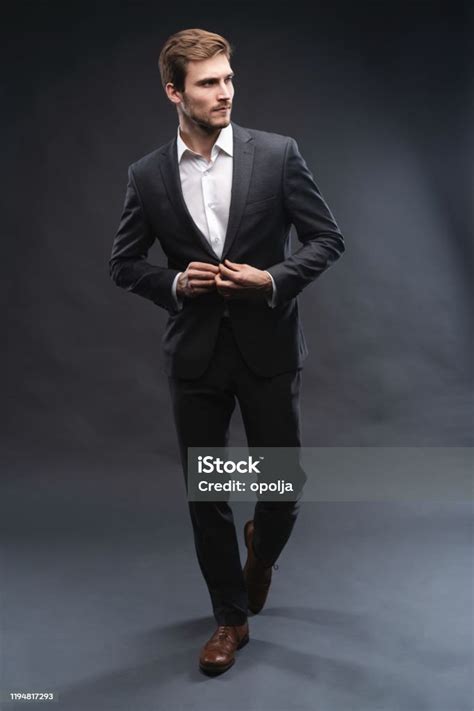 회색 배경 위에 고립 된 양복을 입은 잘 생긴 젊은 사업가의 전체 길이 초상화 포즈 멀리 보고 걷기 걷기에 대한 스톡 사진 및