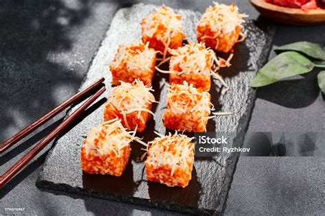 어두운 돌 테이블에 마키 초밥 토비코와 캘리포니아 마키 스시 롤 안에 생선 마구로와 치즈 바깥쪽 검은 배경 나뭇잎 및 단단한 그림자가있는 스타일 컨셉 일본 메뉴 0명에 대한