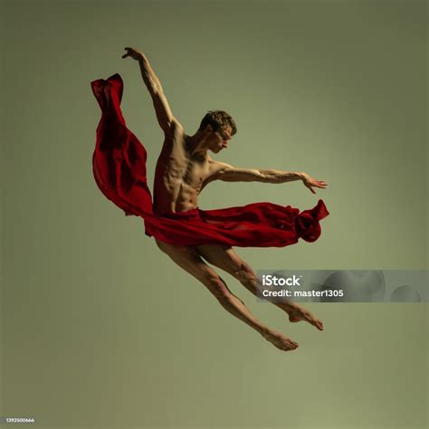 한 젊은 근육질의 남자 빨간 천으로 행동하는 유연한 발레 댄서 올리브 색 배경에 고립 된 천 연극 감정 은혜 예술 아름다움 개념