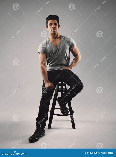 Красивый молодой человек сидя на барном стуле Стоковое Фото изображение насчитывающей парень