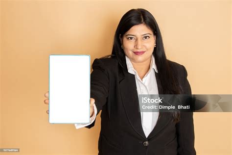 젊은 인도 사업가가 베이지색 배경 위에 격리된 광고를 넣기 위해 빈 디스플레이 화면이 있는 디지털 태블릿을 보여주는 양복을 입고