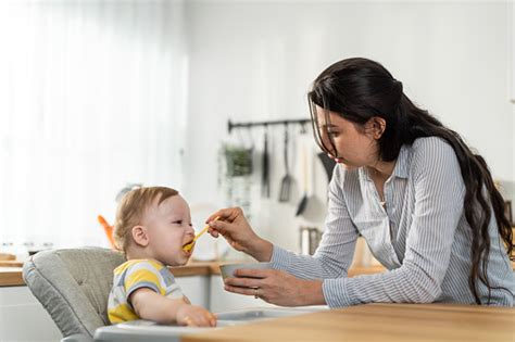 백인 아름다운 어머니는 부엌에서 아기 소년 유아를 돌봅니다 행복한 가족 매력적인 사랑하는 엄마 요리와 집에서 점심 식사를 위해 의자에 앉아있는 동안 어린 아이 아아 유아에게