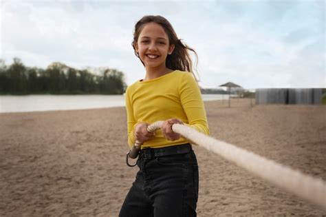 Ragazza Del Tiro Medio Che Gioca Al Tiro Alla Fune Sulla Spiaggia Foto Gratis