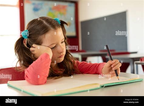 Girl Writing On Notebook In A Classroom Stock Photo Alamy