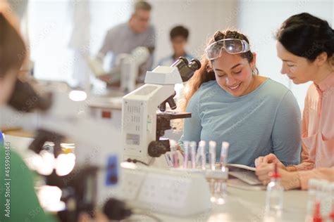 Female Teacher And Girl Babe Conducting Scientific Experiment At Microscope In Laboratory