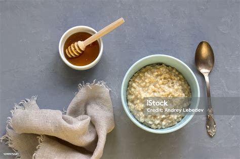 버터와 다진 빨간 사과와 함께 푸른 그릇에 담긴 오트밀 죽의 아침 식사 나무 꿀 숟가락이있는 흰색 그릇에 꿀 콘크리트 배경 여유 공간 상단 보기 0명에 대한 스톡 사진 및