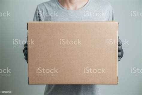 회색 배경에 제품을 제공하기위한 골판지 상자를 들고 검은 장갑을 가진 남자의 세부 사항 Store Opening에 대한 스톡 사진 및 기타 이미지 Store
