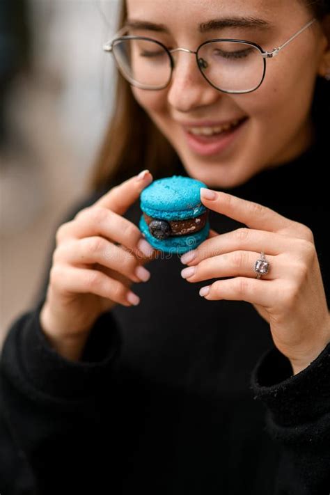 Young Woman Is Going To Eat Sweet Macaroon While Holding It In Her Hand